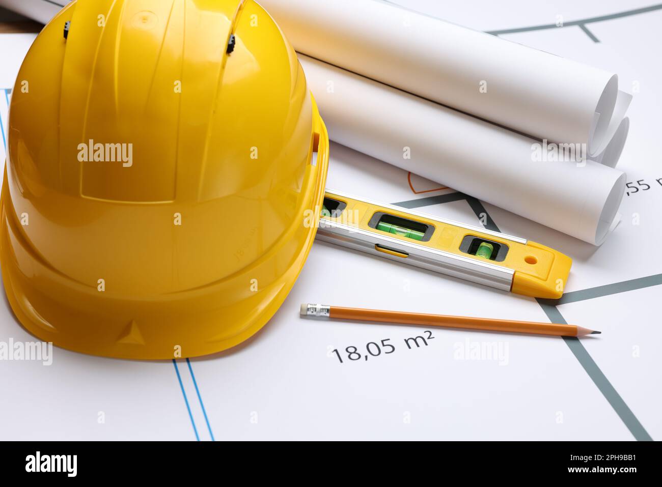 Rolled construction drawings, safety hat, pencil and bubble level on ...