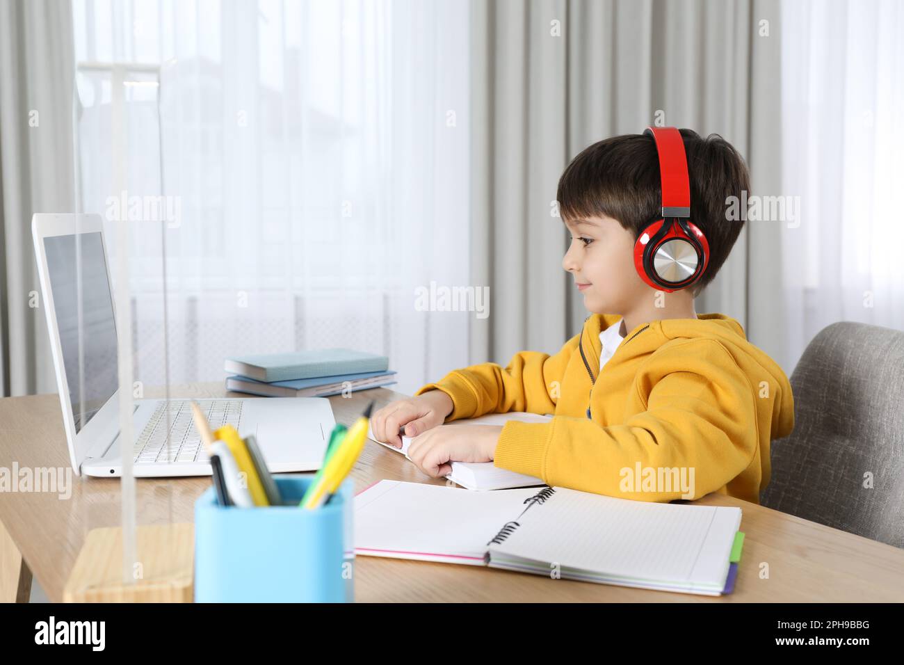 Cute little boy with modern laptop studying online at home. E-learning ...