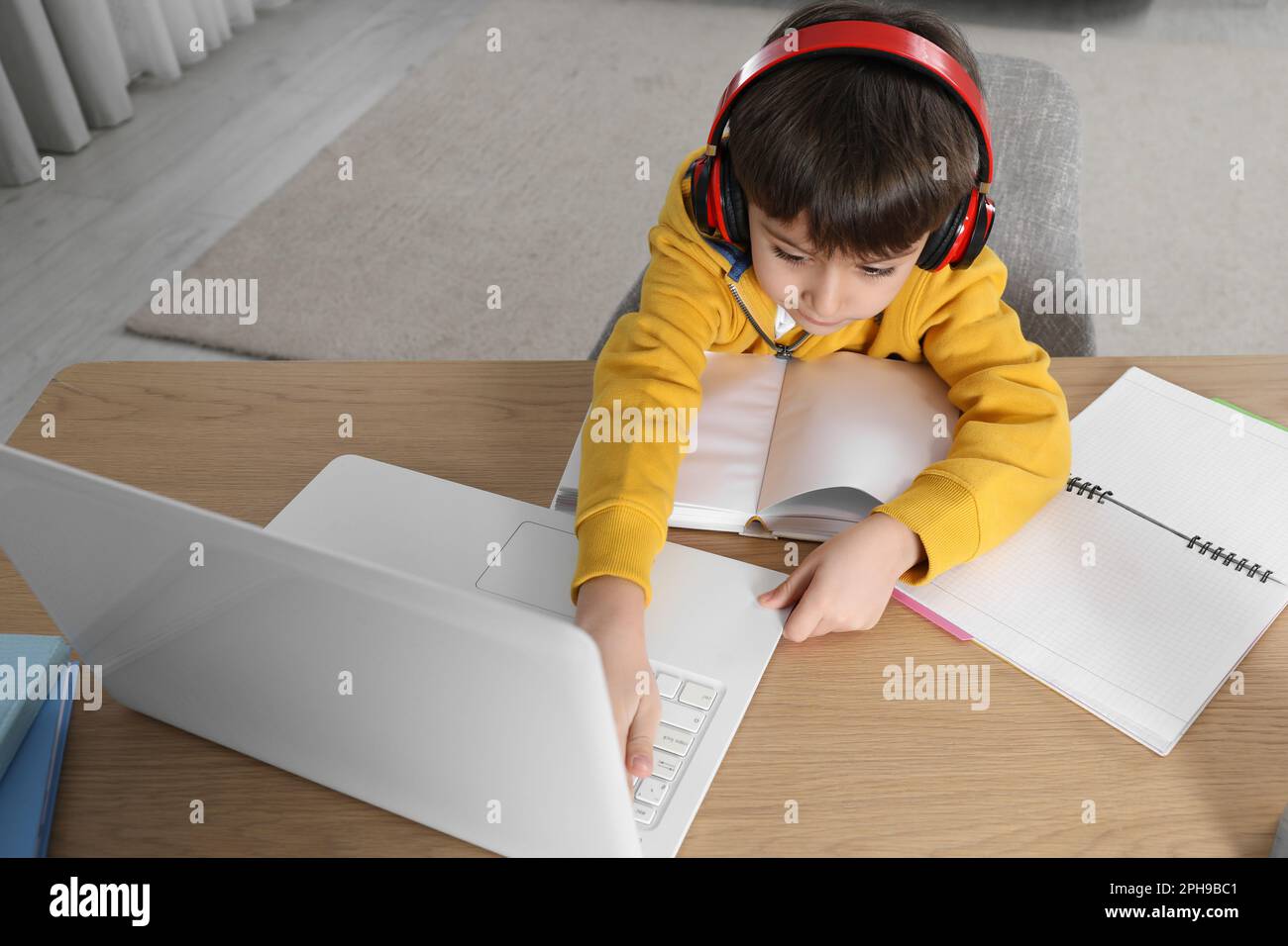 Cute little boy with modern laptop studying online at home. E-learning ...