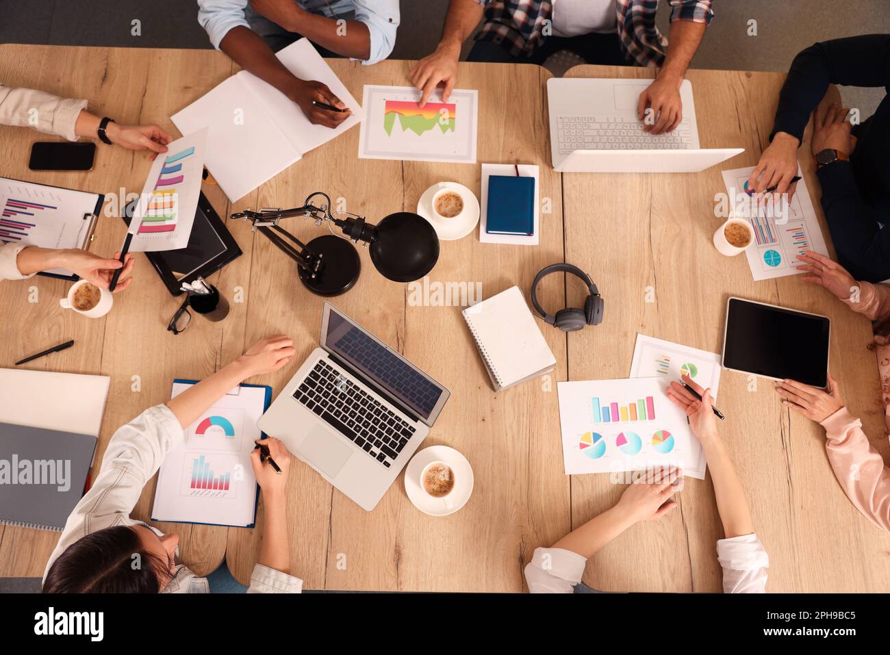 Team of employees working together at wooden table, above view. Startup ...