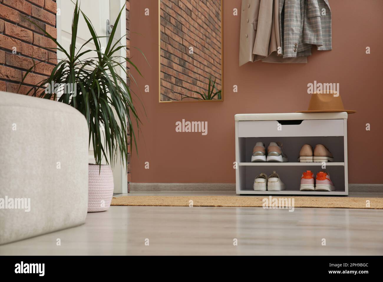 Rack with different shoes near pale pink wall in hall Stock Photo - Alamy