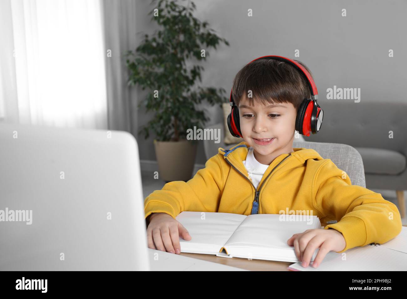 Cute little boy with modern laptop studying online at home. E-learning ...