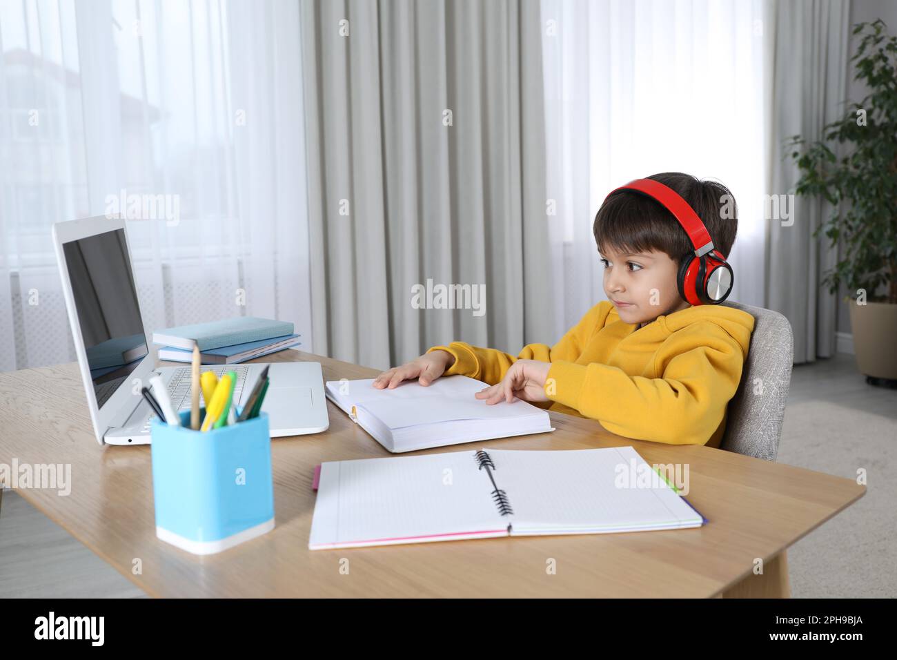 Cute little boy with modern laptop studying online at home. E-learning ...