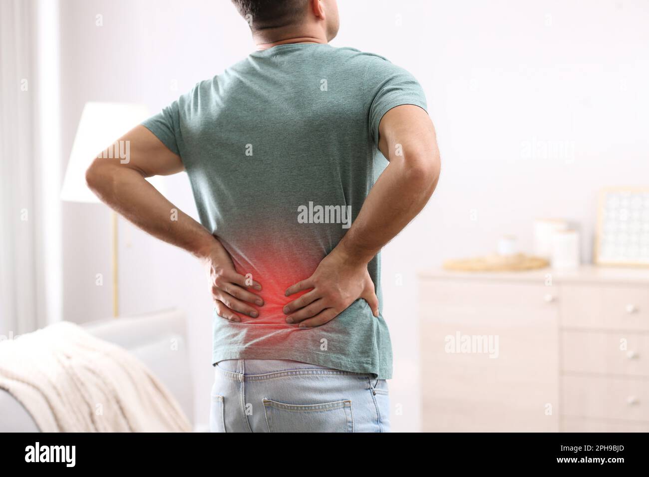 Man suffering from back pain at home. Bad posture problem Stock Photo ...