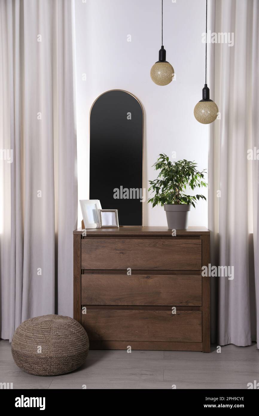 Stylish room interior with wooden chest of drawers and beautiful decor ...