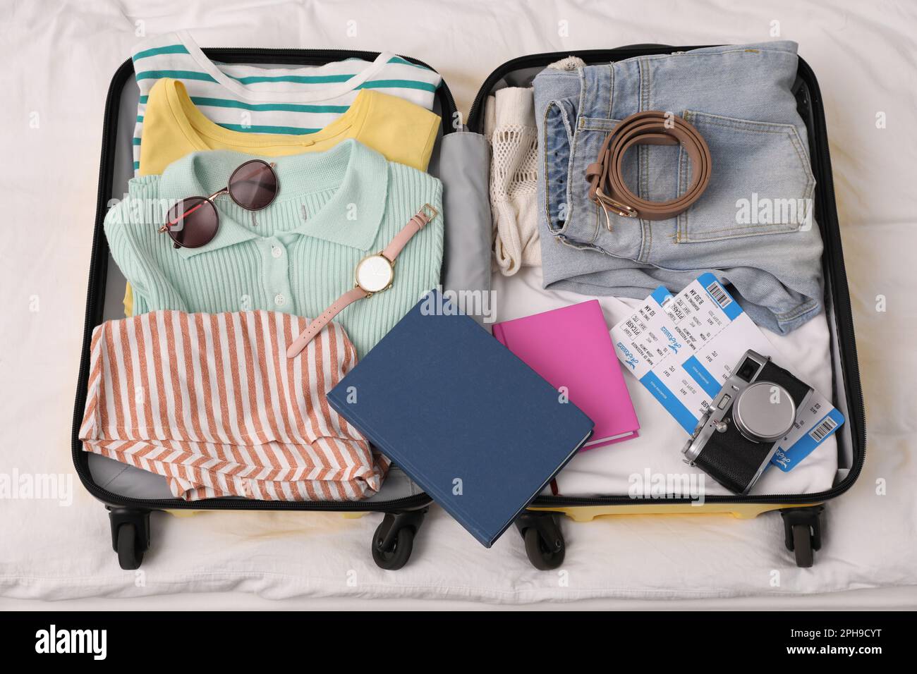 Open suitcase with clothes and accessories on bed, top view Stock Photo ...