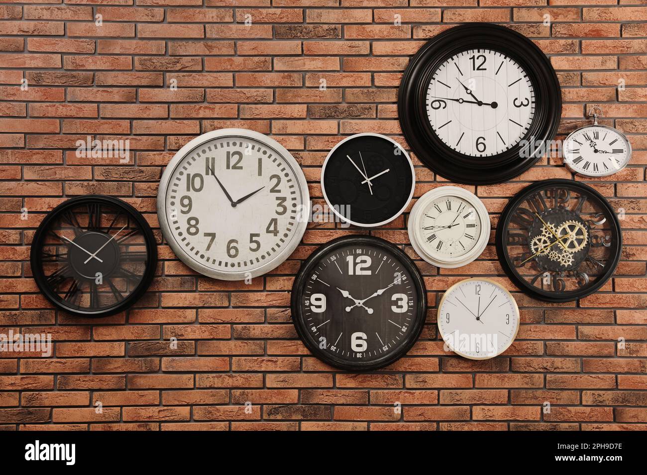 Collection of clocks hanging on red brick wall Stock Photo - Alamy