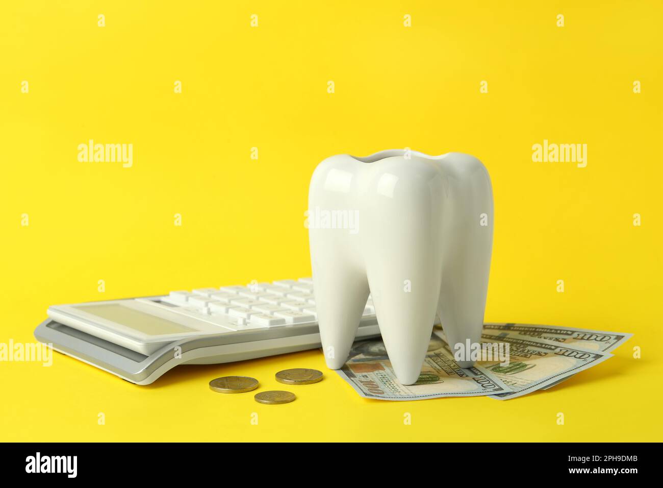 Ceramic model of tooth, money and calculator on yellow background ...