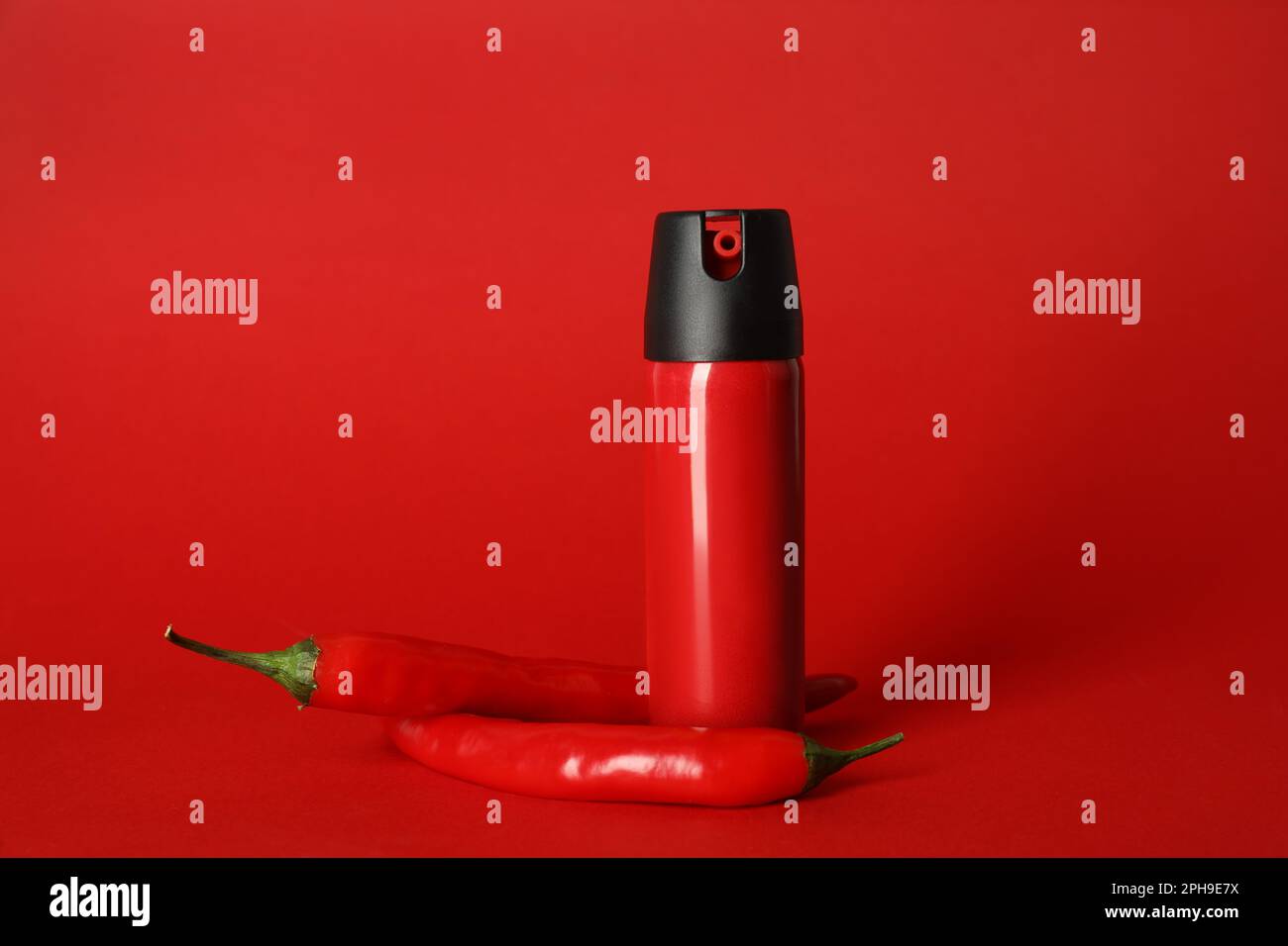 Bottle of gas pepper spray and fresh chili peppers on red background ...
