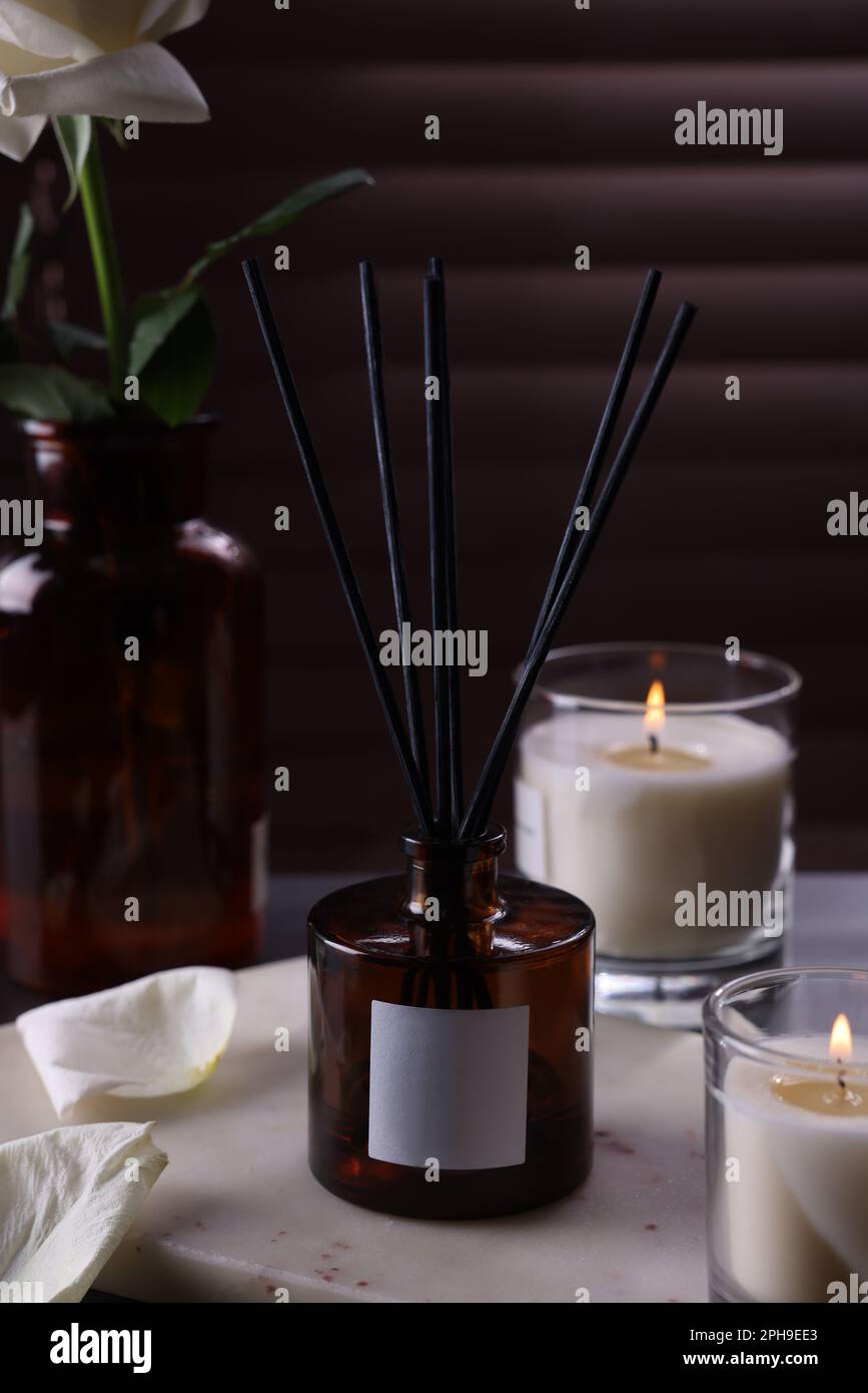 Aromatic reed air freshener and burning candles on white board near ...