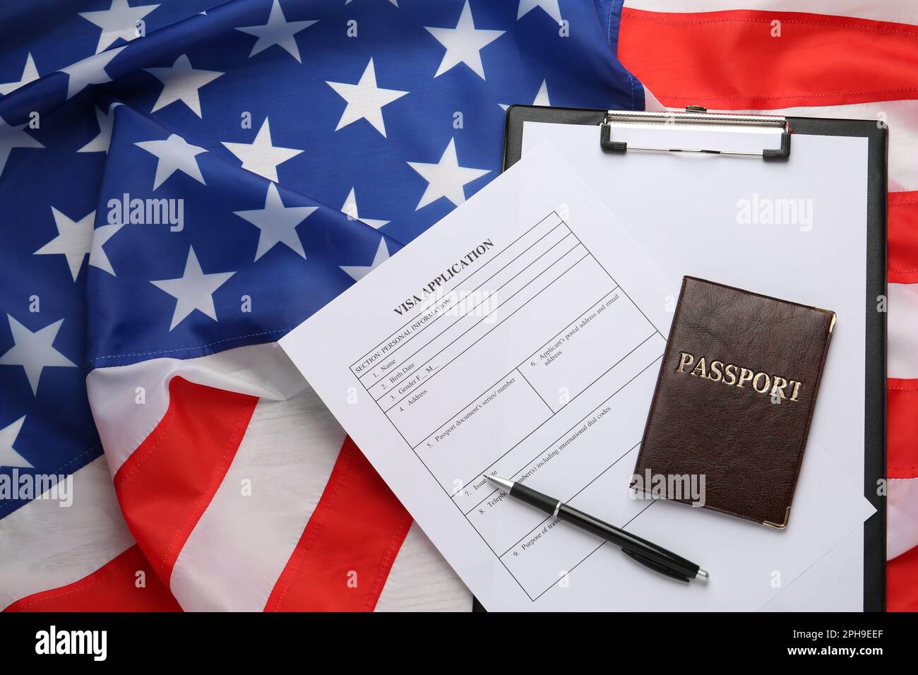 Visa application form, clipboard and passport on American flag, top ...