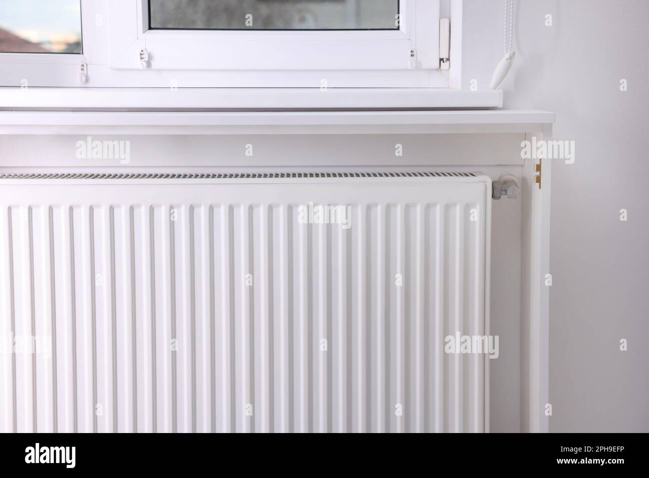 Modern radiator on wall under window indoors. Central heating system ...