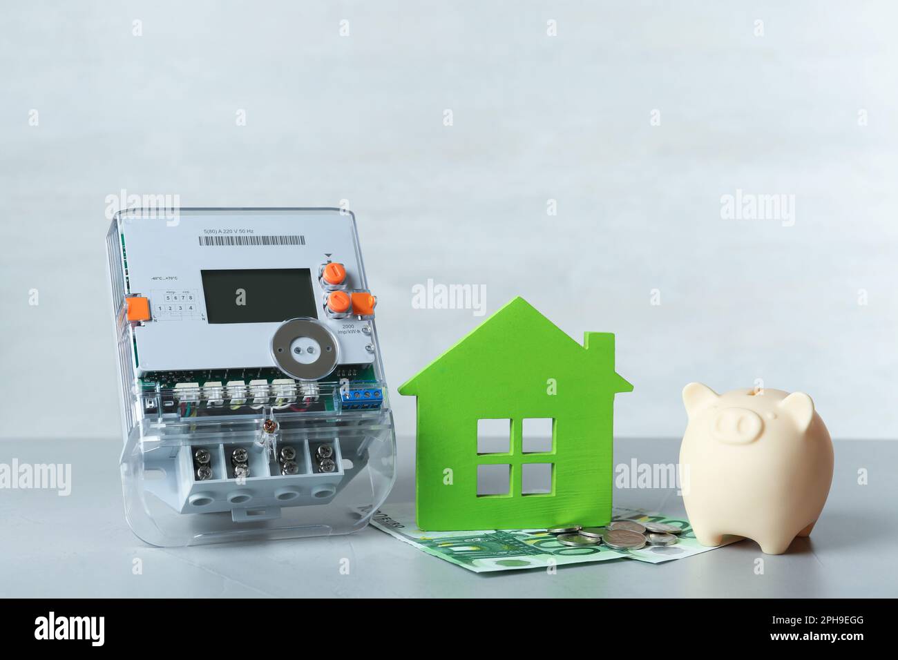 Electricity meter, piggy bank and euro banknotes on grey table Stock ...