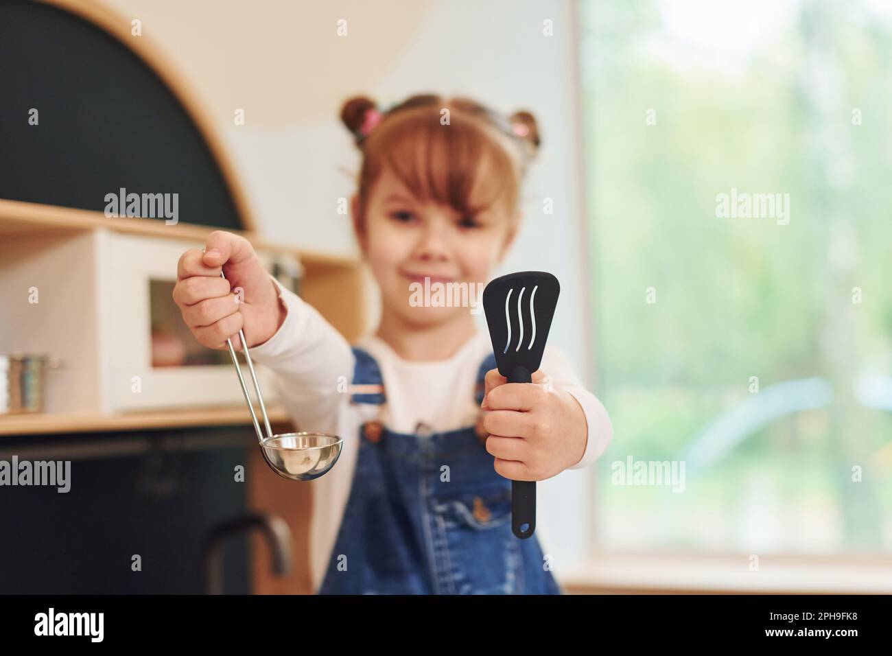 Holding tools in hands and shows it. Little girl in casual clothes have ...