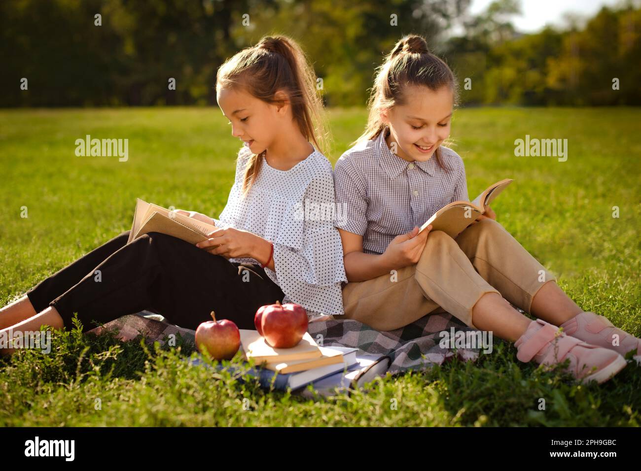 two happy girls friends reading in green park. prepare together for ...