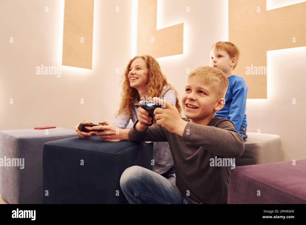 Cheerful kids sitting indoors and playing video games together Stock ...