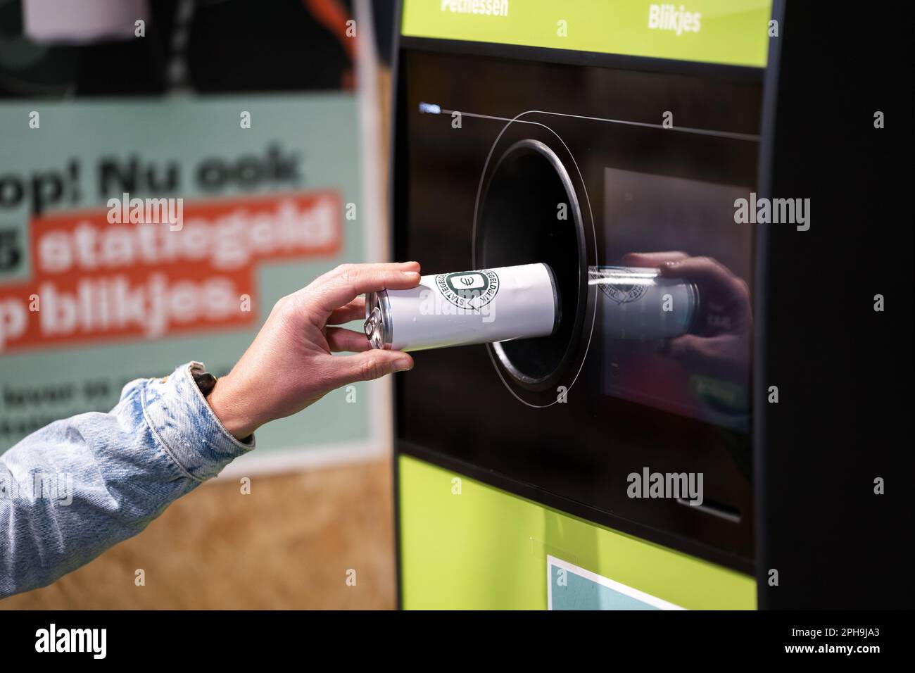 ALMERE - A consumer symbolically hands over a can at a collection point ...