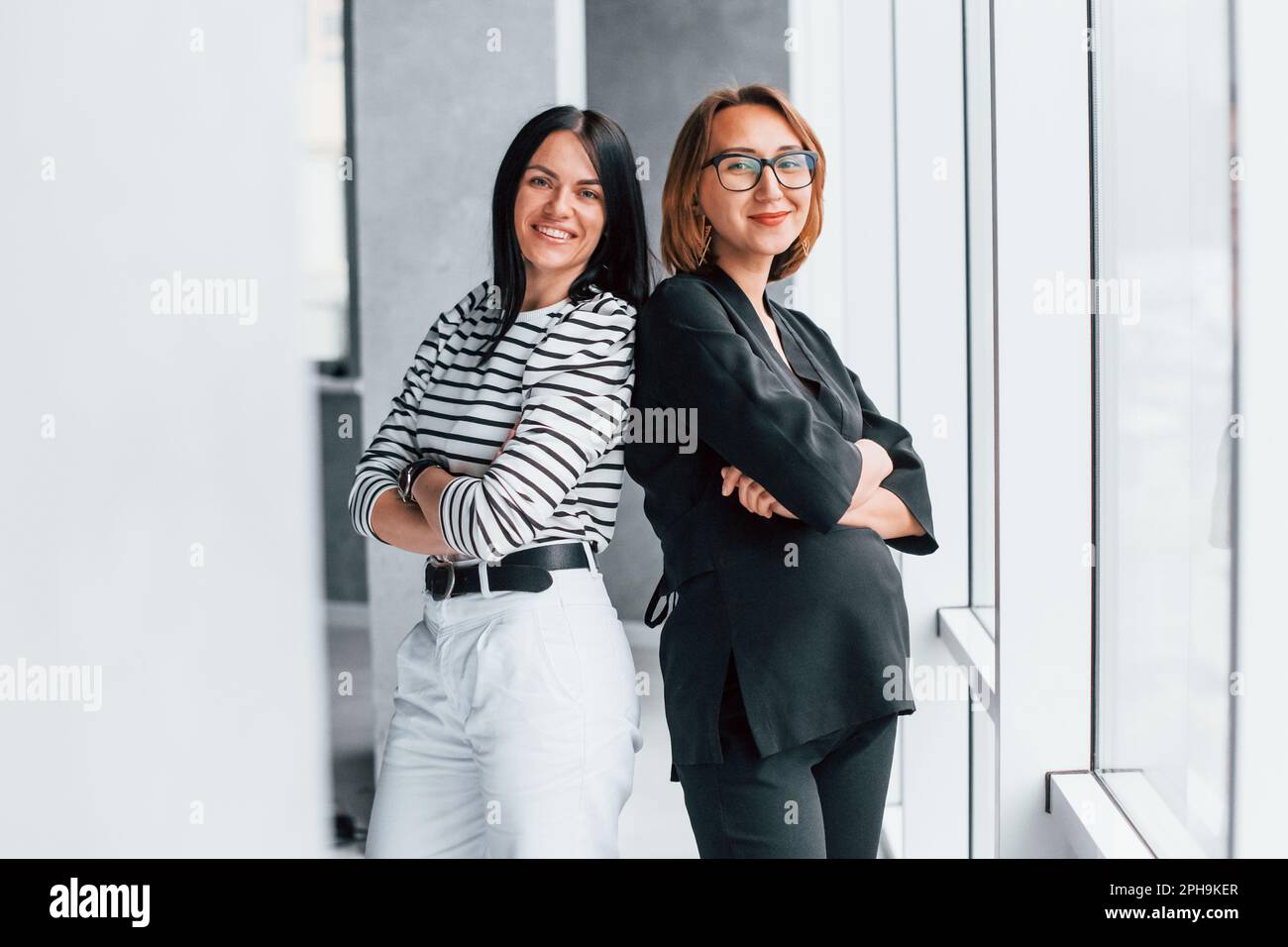 Two business women standing together indoors in the office near big ...