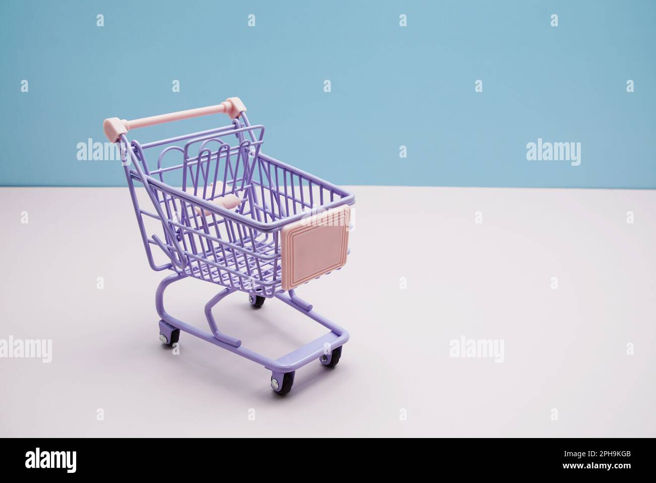 Purple trolley shopping cart with space copy on blue and pink ...