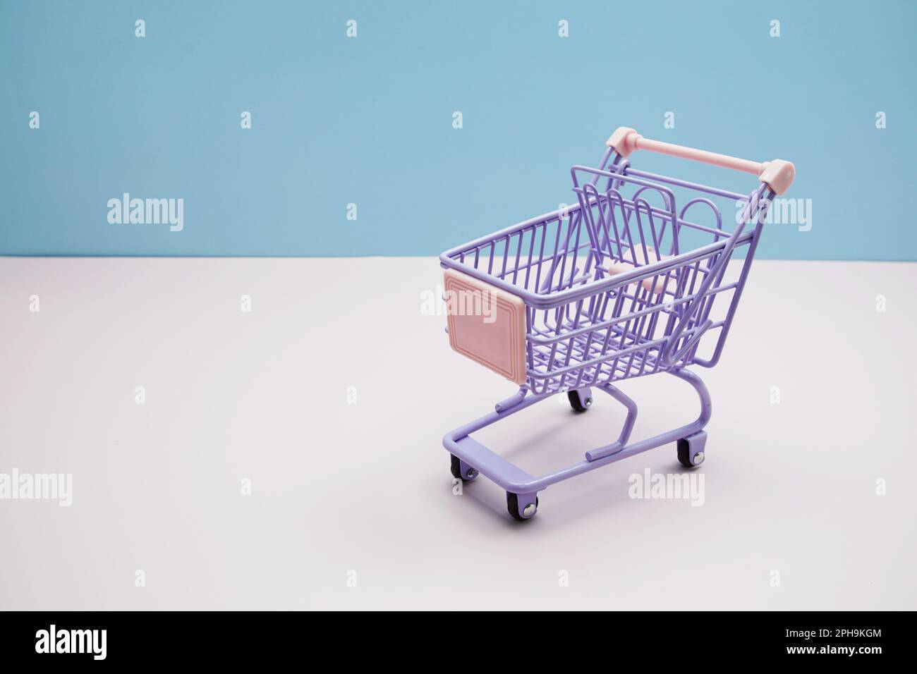 Purple trolley shopping cart with space copy on blue and pink ...