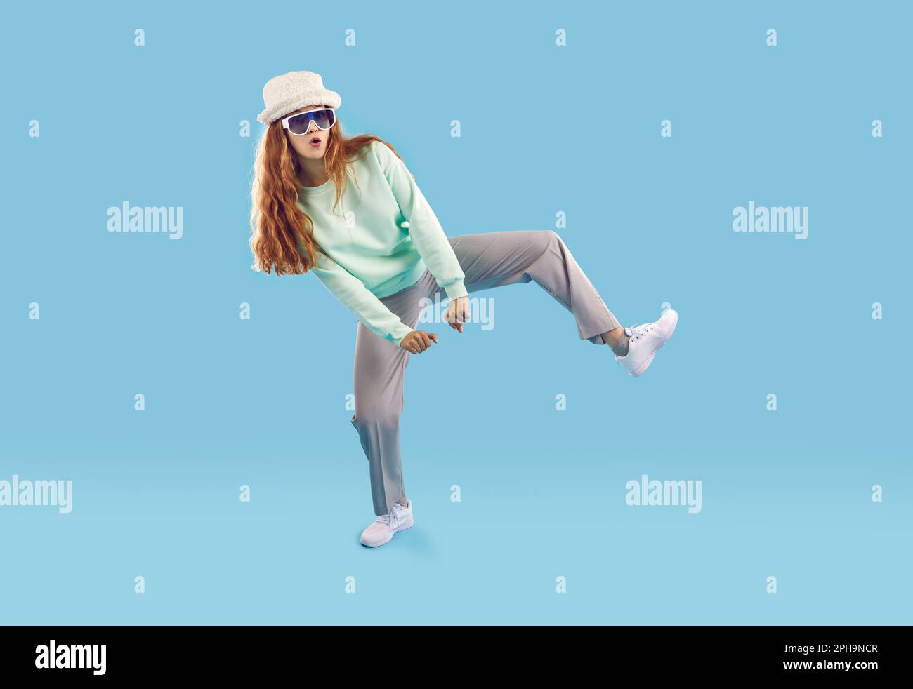 Cheerful young woman jokingly fooling around showing funny movements on ...