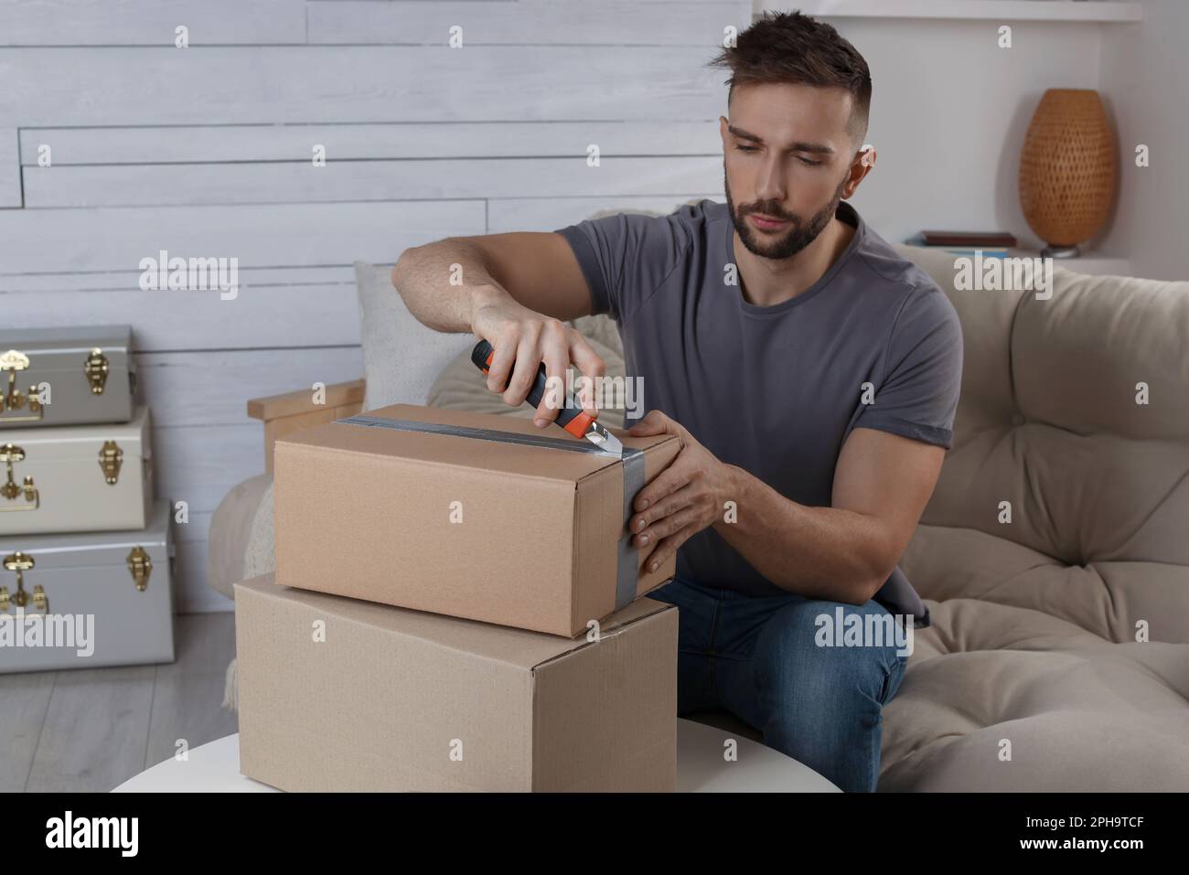 Man using utility knife to open parcel at home Stock Photo - Alamy