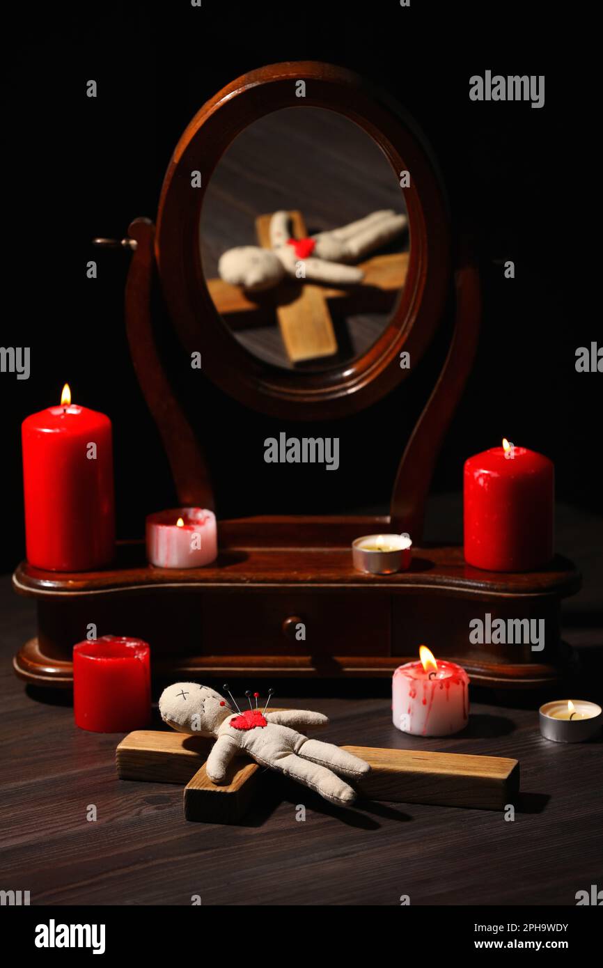 Voodoo doll with pins in heart and ceremonial items on wooden table ...