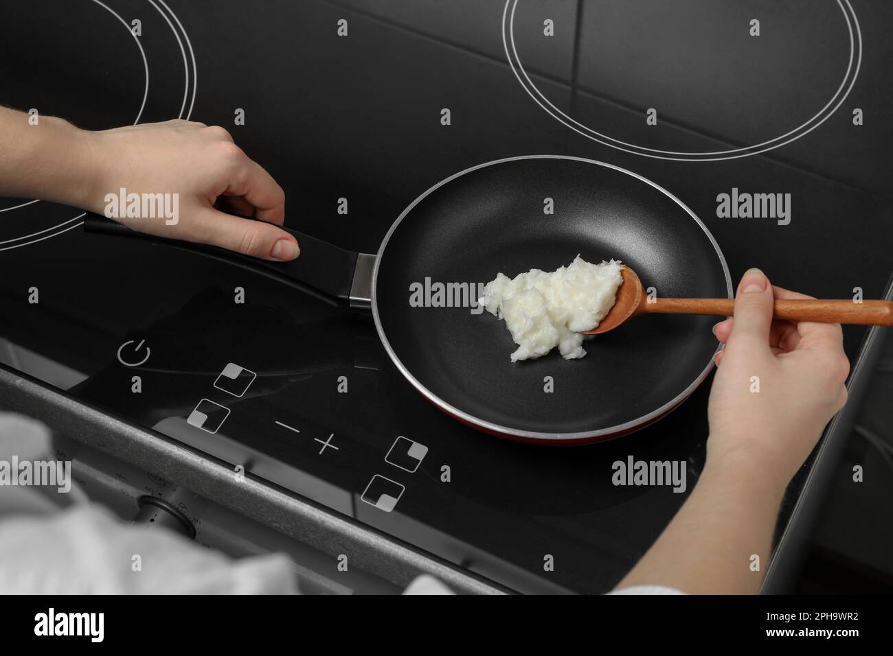 Woman cooking with coconut oil on induction stove, closeup Stock Photo ...