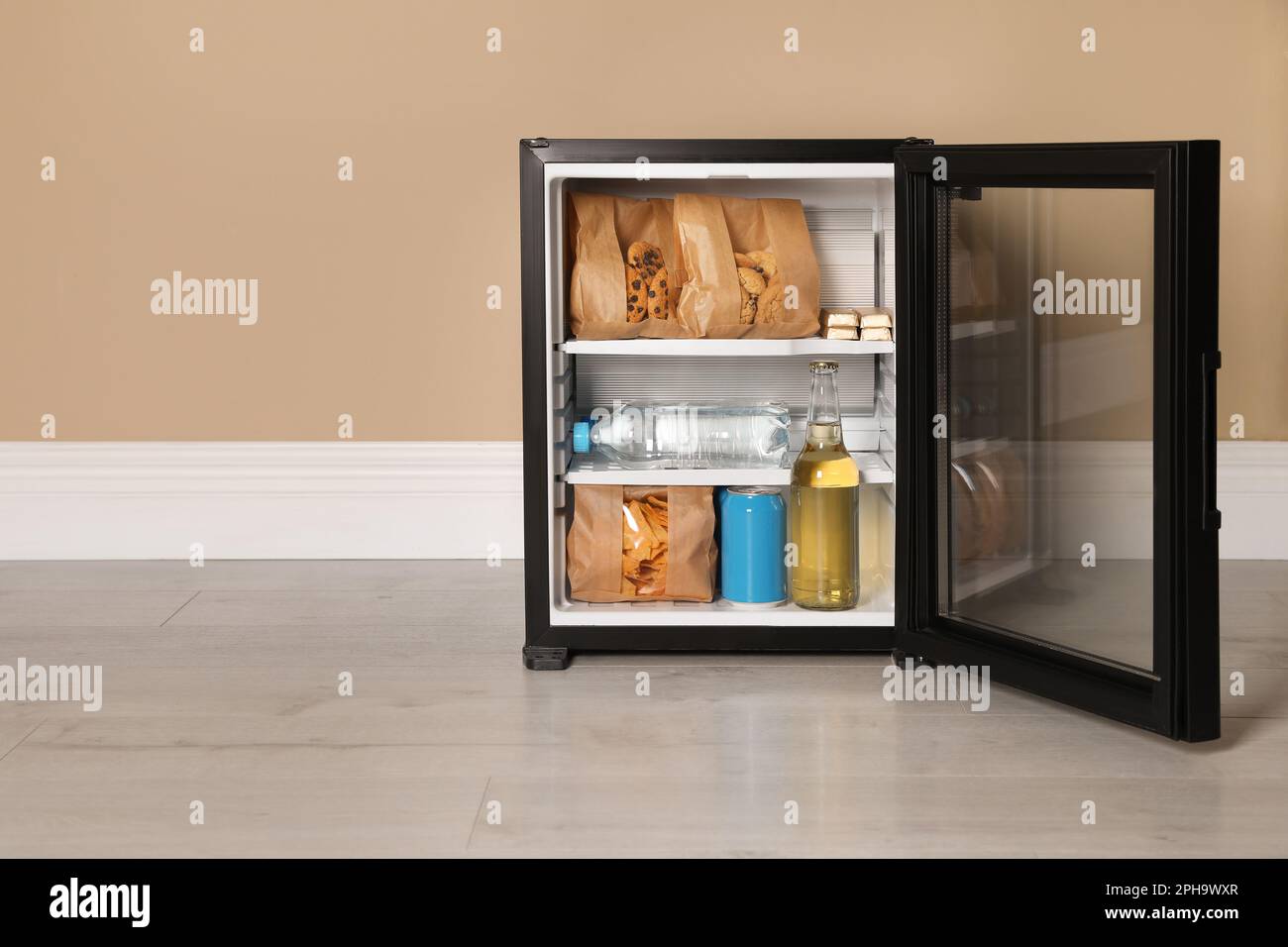 Mini bar filled with food and drinks near beige wall indoors, space for ...