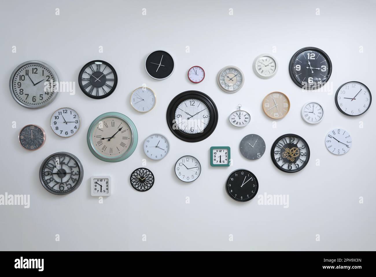 Collection of different clocks hanging on white wall Stock Photo - Alamy