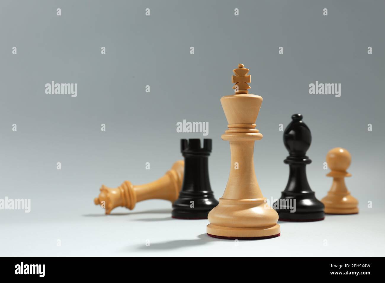 Different chess pieces against light background, focus on white king ...