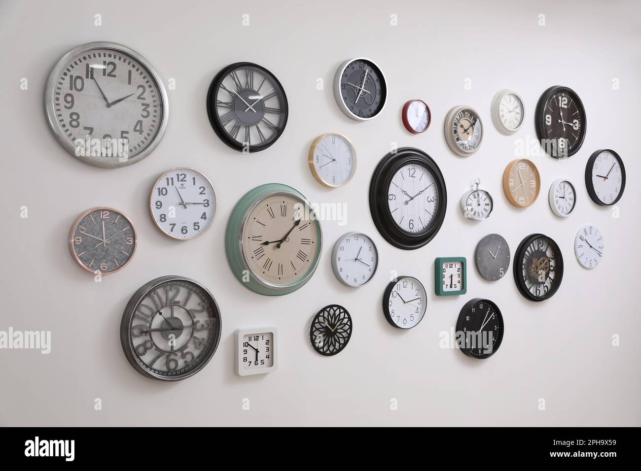 Collection of different clocks hanging on white wall Stock Photo - Alamy