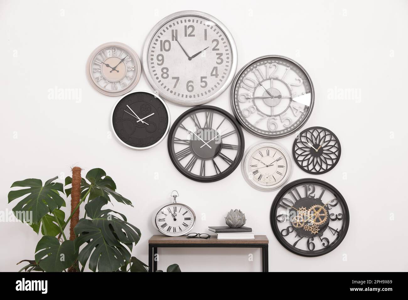 Console table, beautiful houseplant and collection of different clocks ...