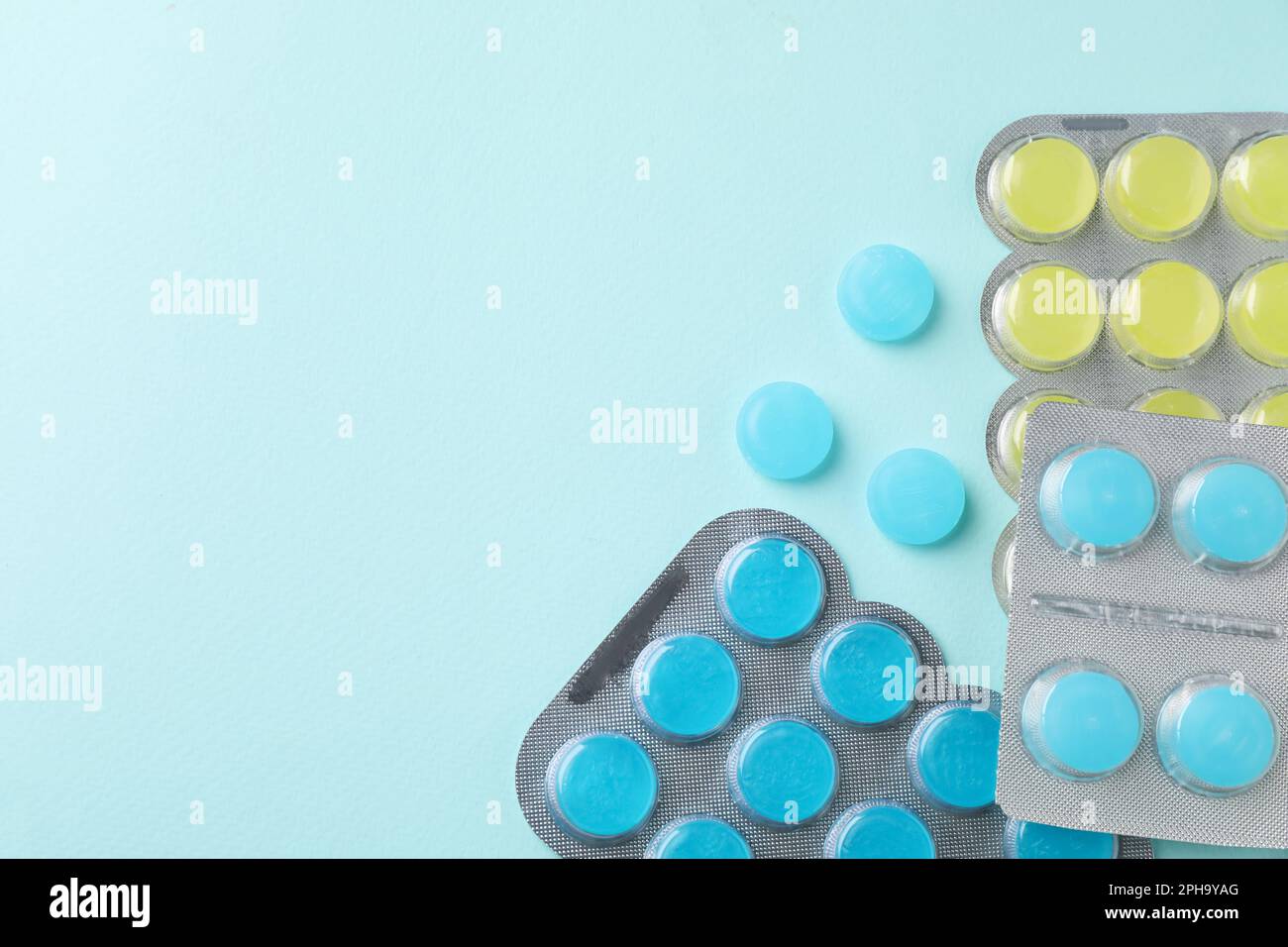 Colorful cough drops on light blue background, flat lay. Space for text ...