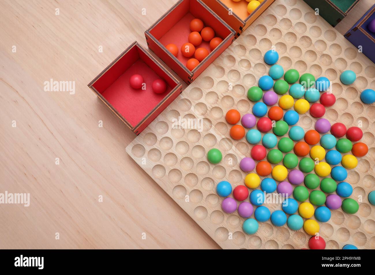 Wooden sorting board and boxes with colorful balls on table, top view ...