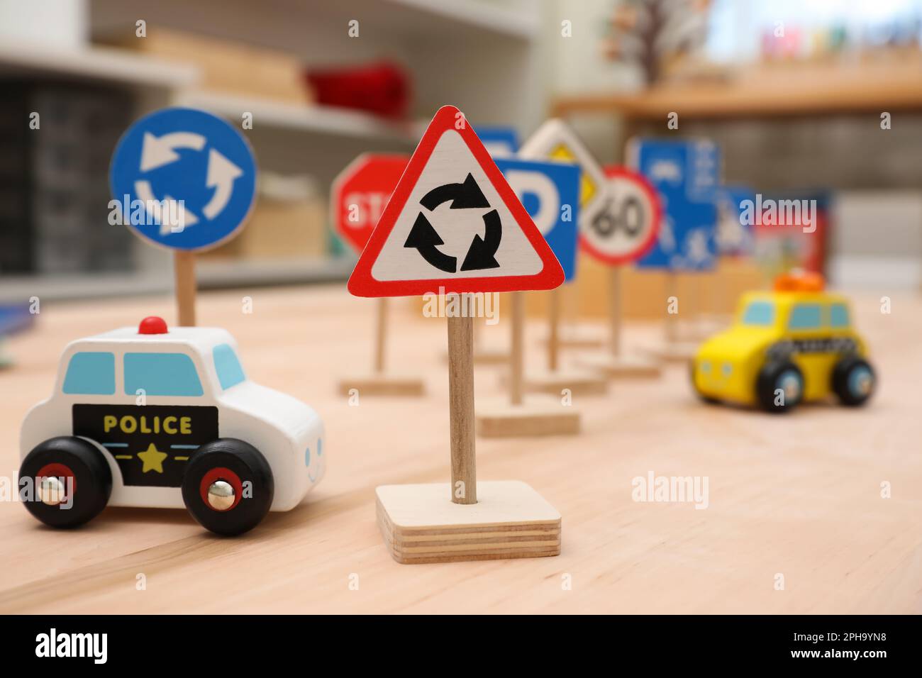 Different miniature road signs and cars on wooden table. Montessori toy ...