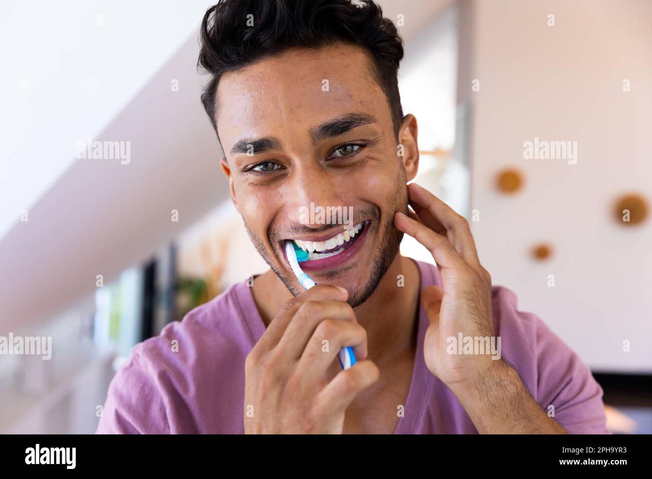 Portrait of smiling biracial man brushing teeth in bathroom Stock Photo ...