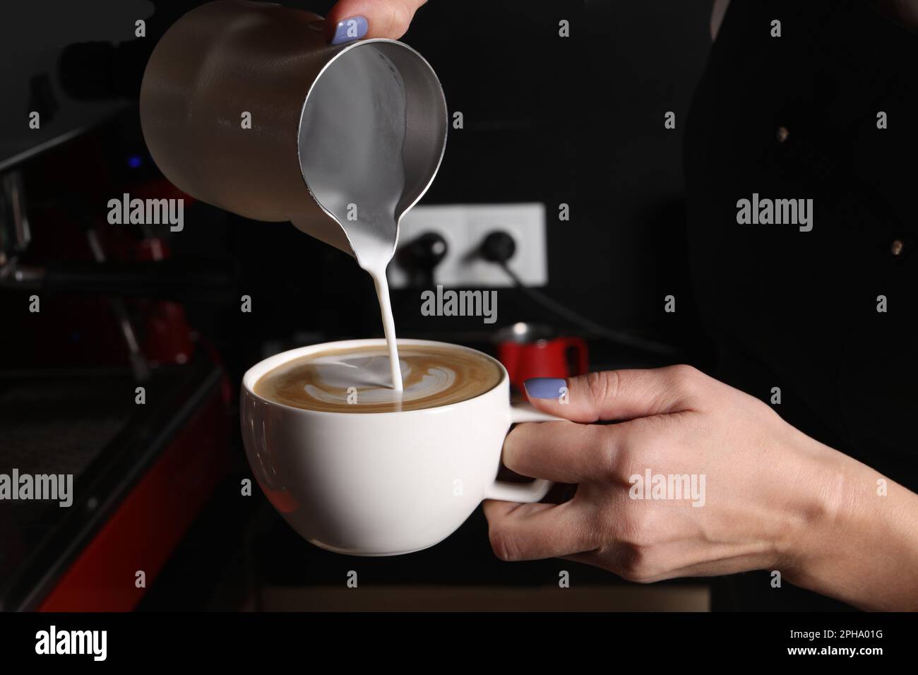 Barista pouring steamed milk from pitcher into cup of aromatic coffee ...