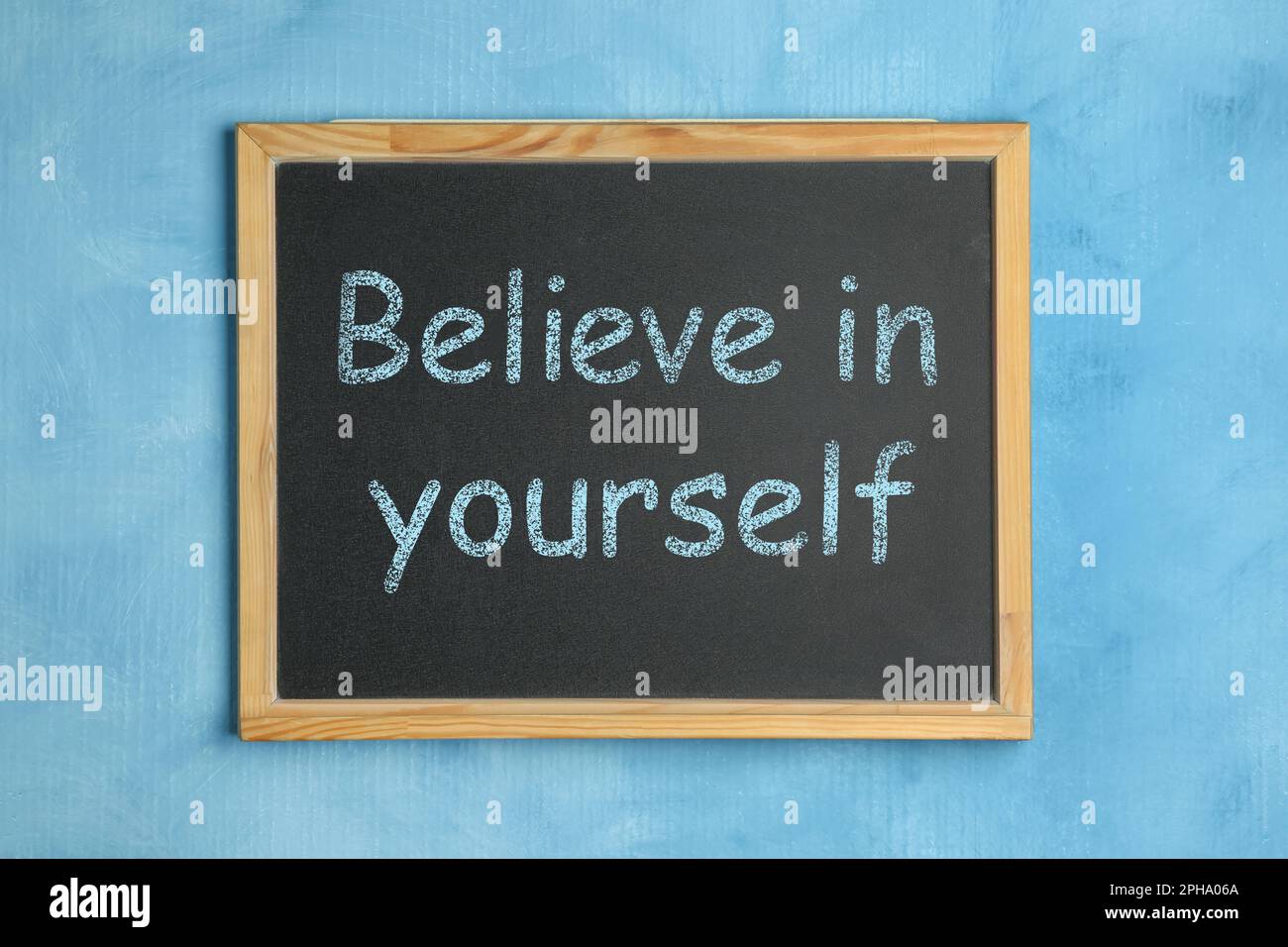 Small chalkboard with motivational quote Believe in yourself on light ...