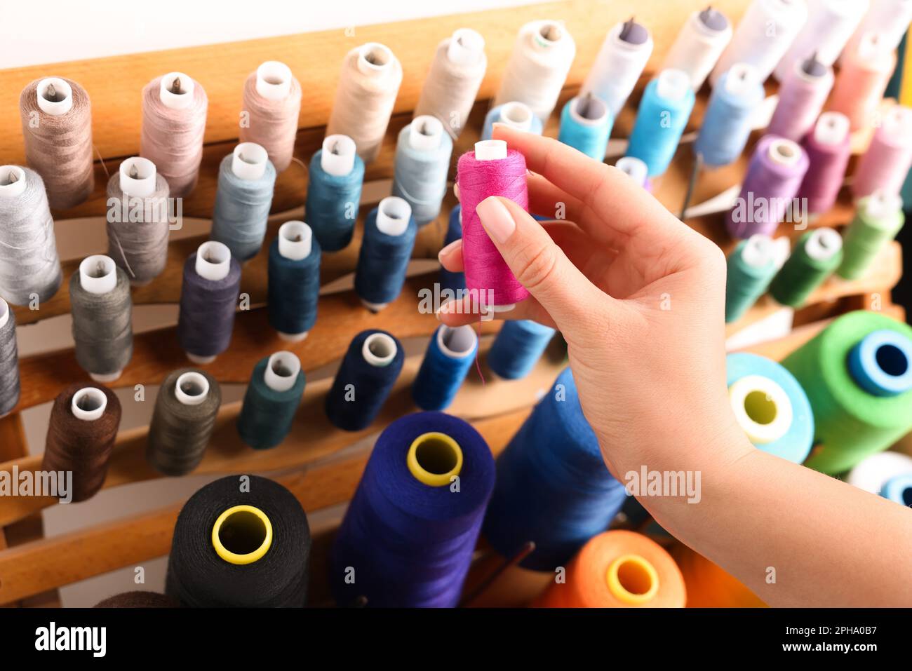 Dressmaker taking pink thread from stand, closeup Stock Photo - Alamy