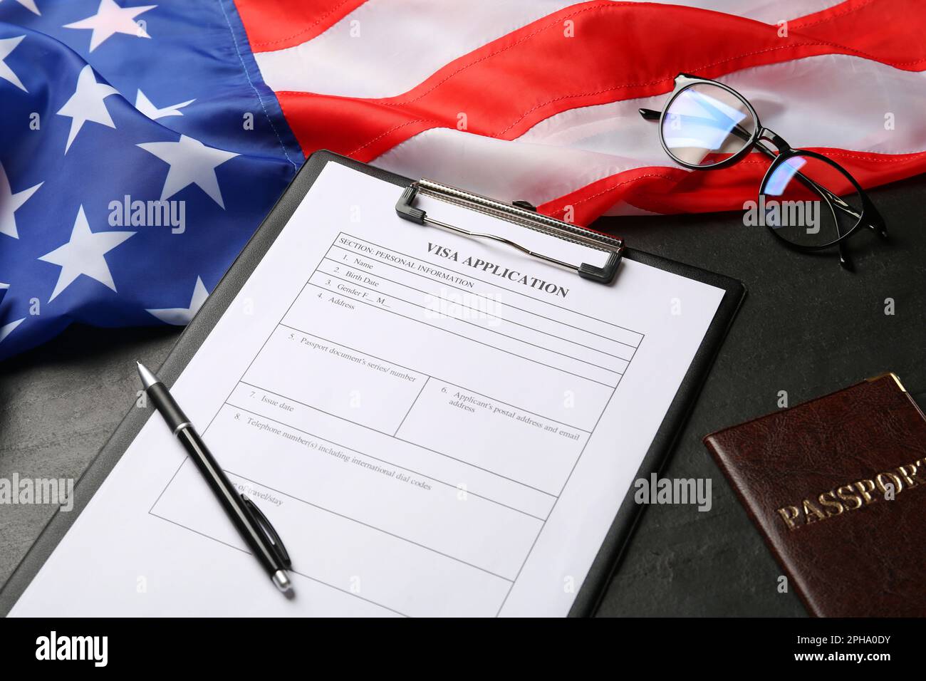 American flag, visa application form, passport and glasses on black ...