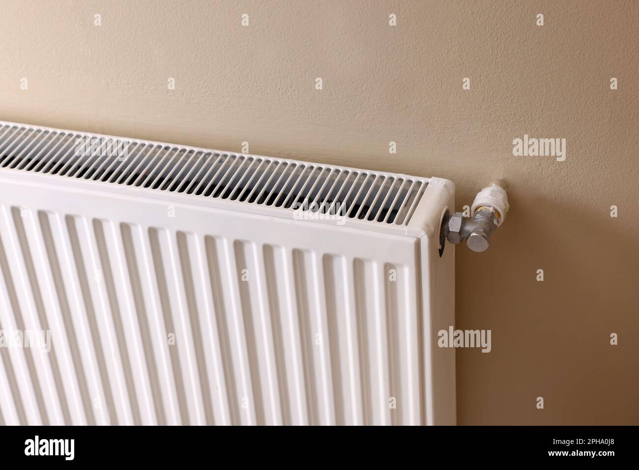 Modern radiator on beige wall. Central heating system Stock Photo - Alamy