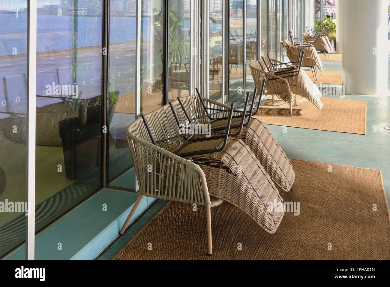 Wicker chairs turned upside down on benches before opening time outside ...