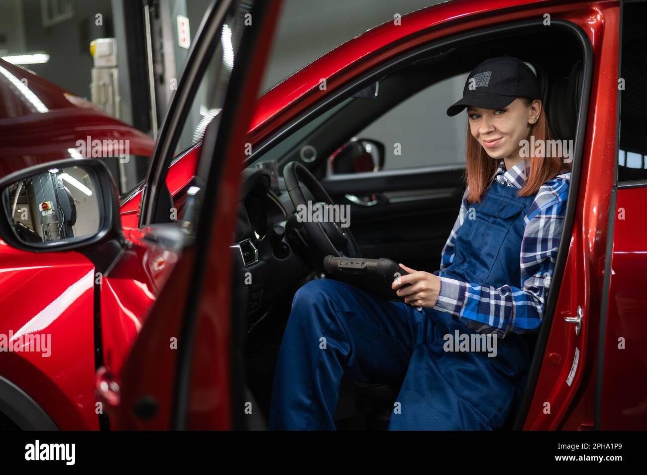 Caucasian female auto mechanic uses a special computer to diagnose ...