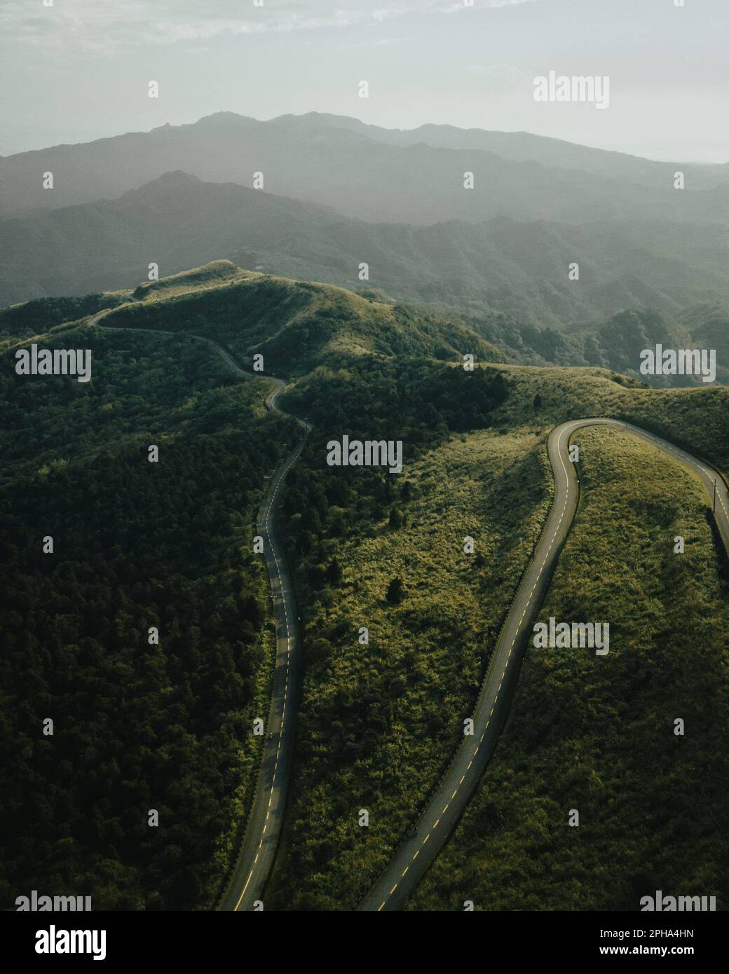 A scenic aerial view of a winding mountain road surrounded by lush ...
