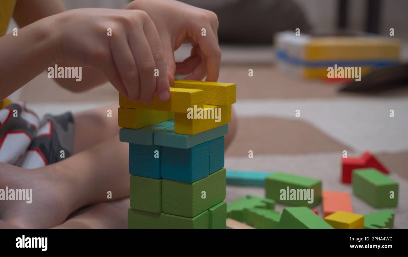 The child builds an imaginary tower of wooden multi-colored cubes ...