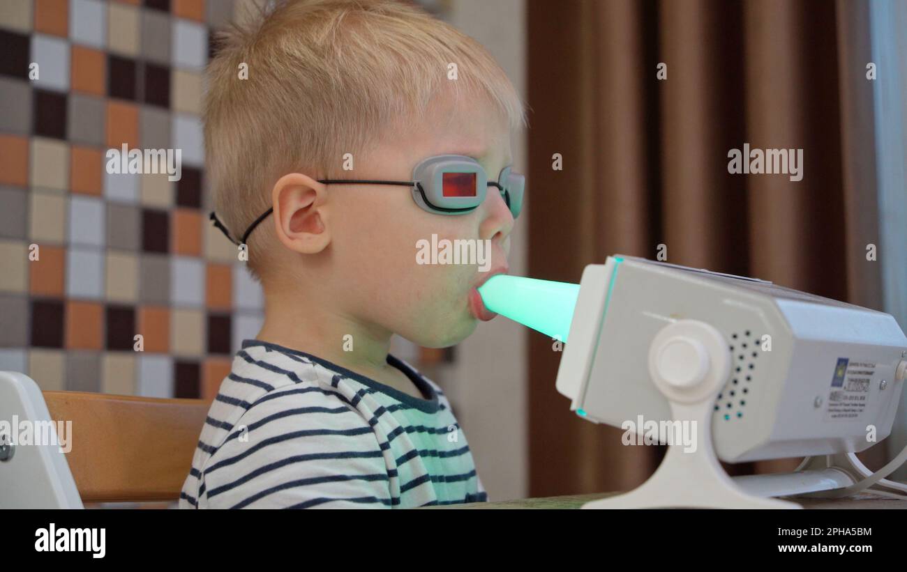 A sick blond boy doing inhalation manipulations treats a cold of the ...