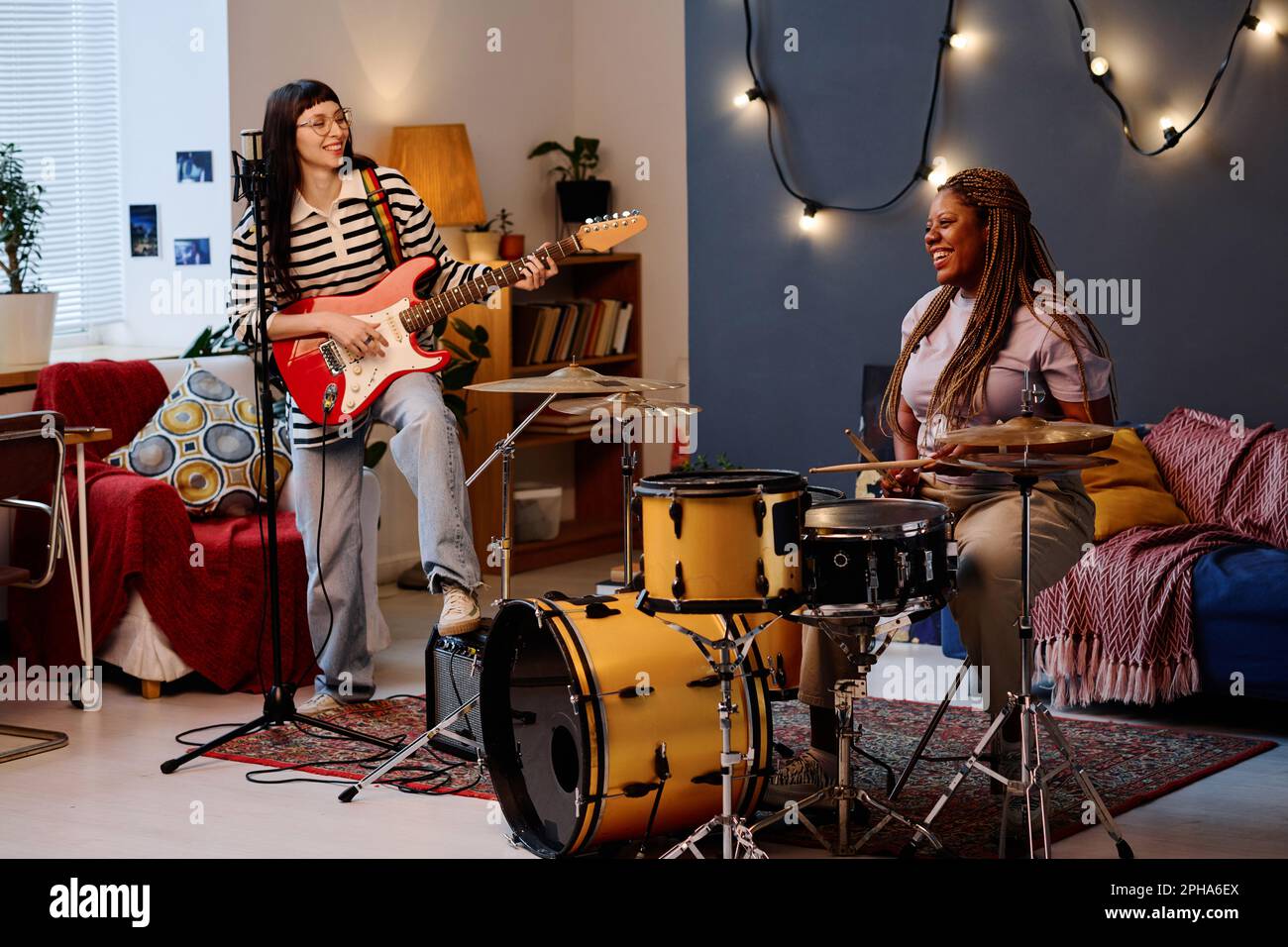 Young women playing guitar and drums together in studio during ...
