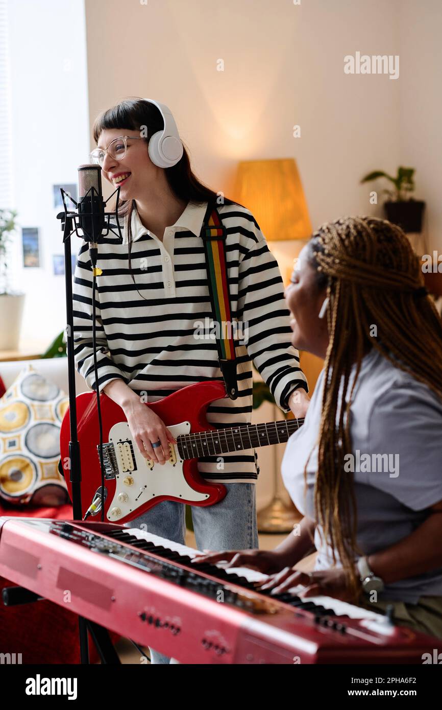 Vertical image of musical women band performing in studio, they playing ...