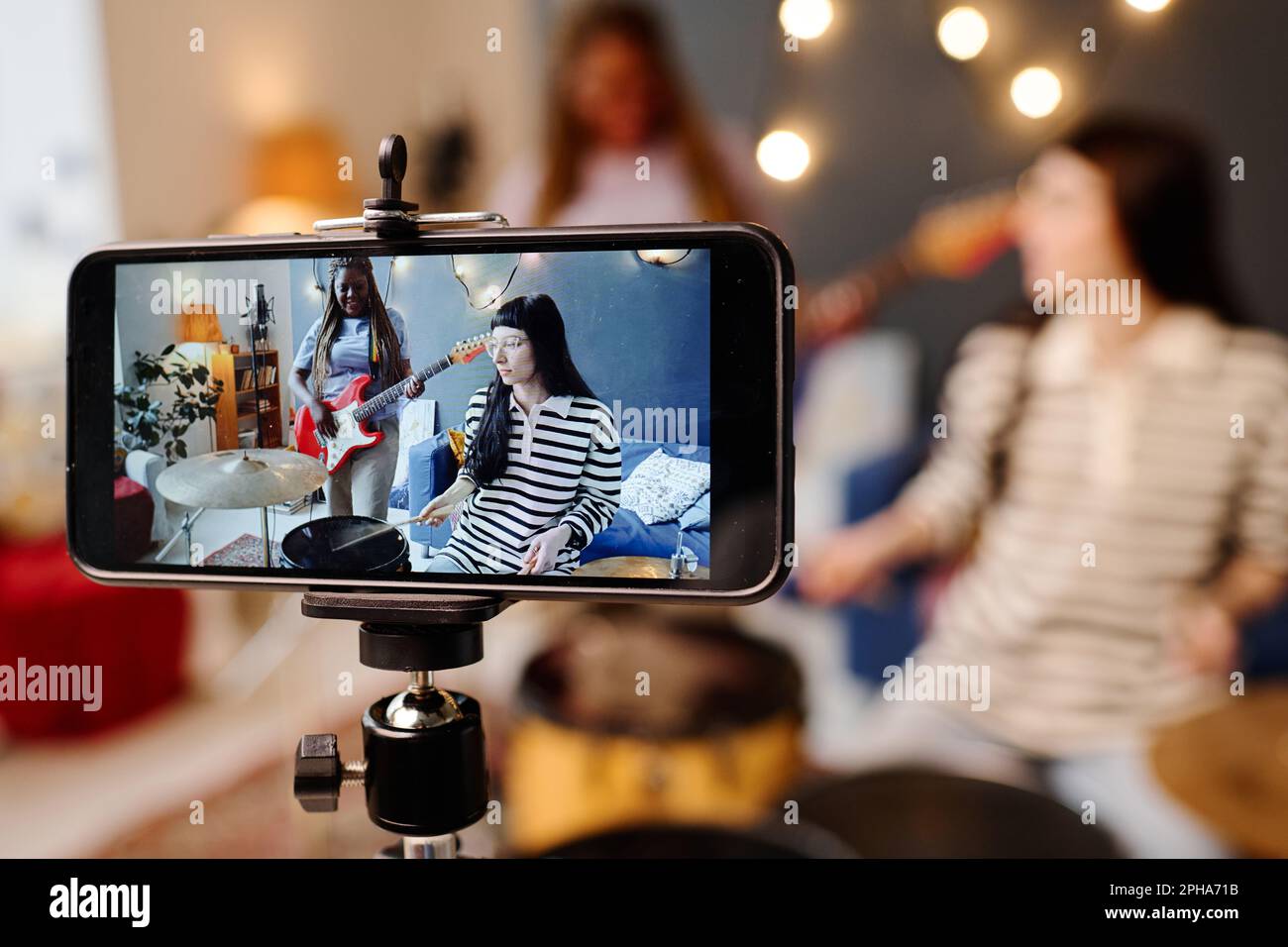 Girls recording their performance on smartphone, they playing guitar ...